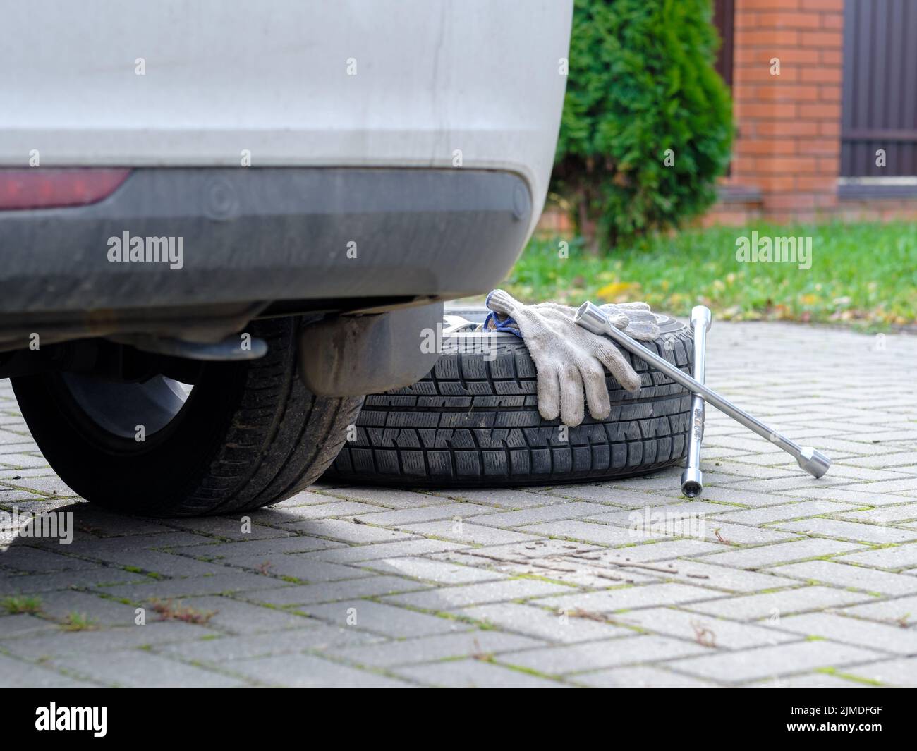 A wrench and work gloves lie on a winter car wheel lying on the ground ...