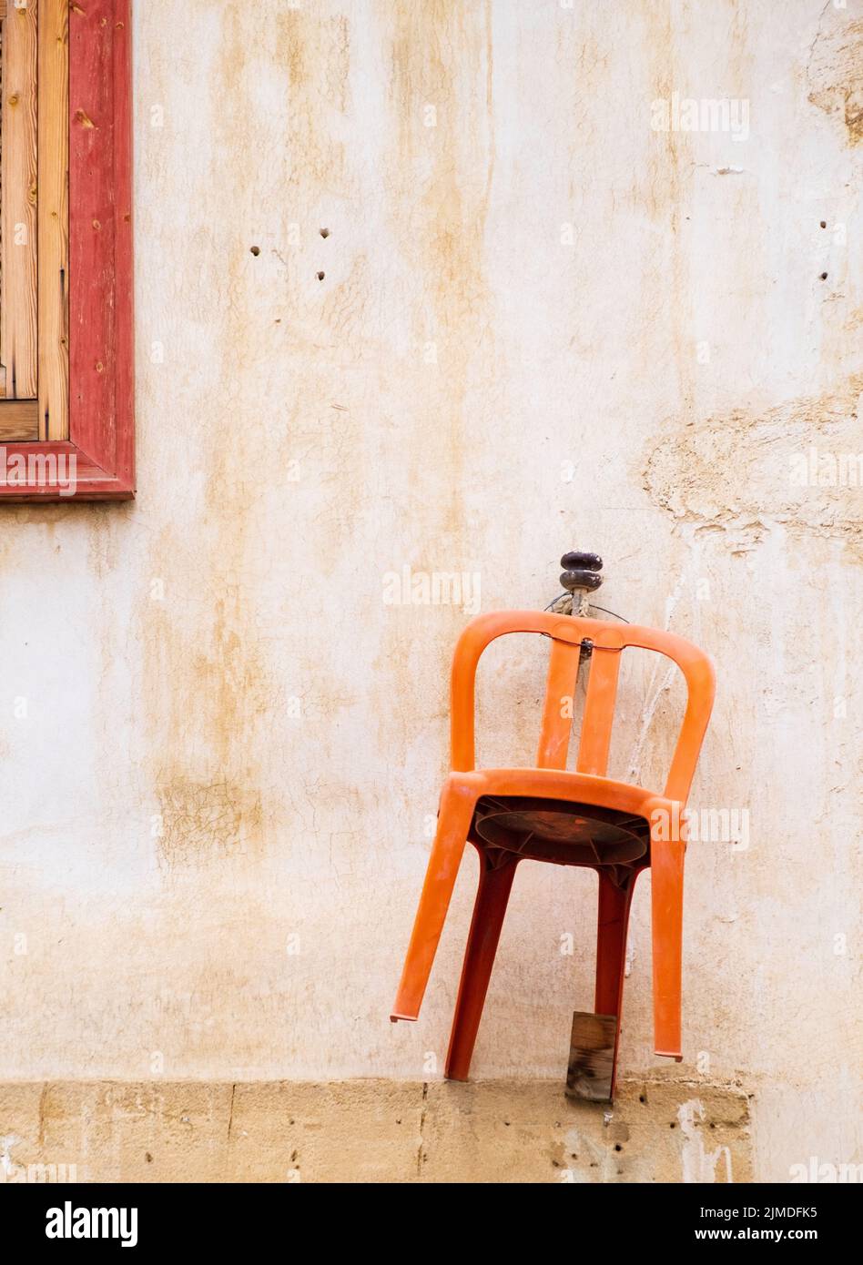 Orange chair hanging on the wall of a traditional house in the old city ...