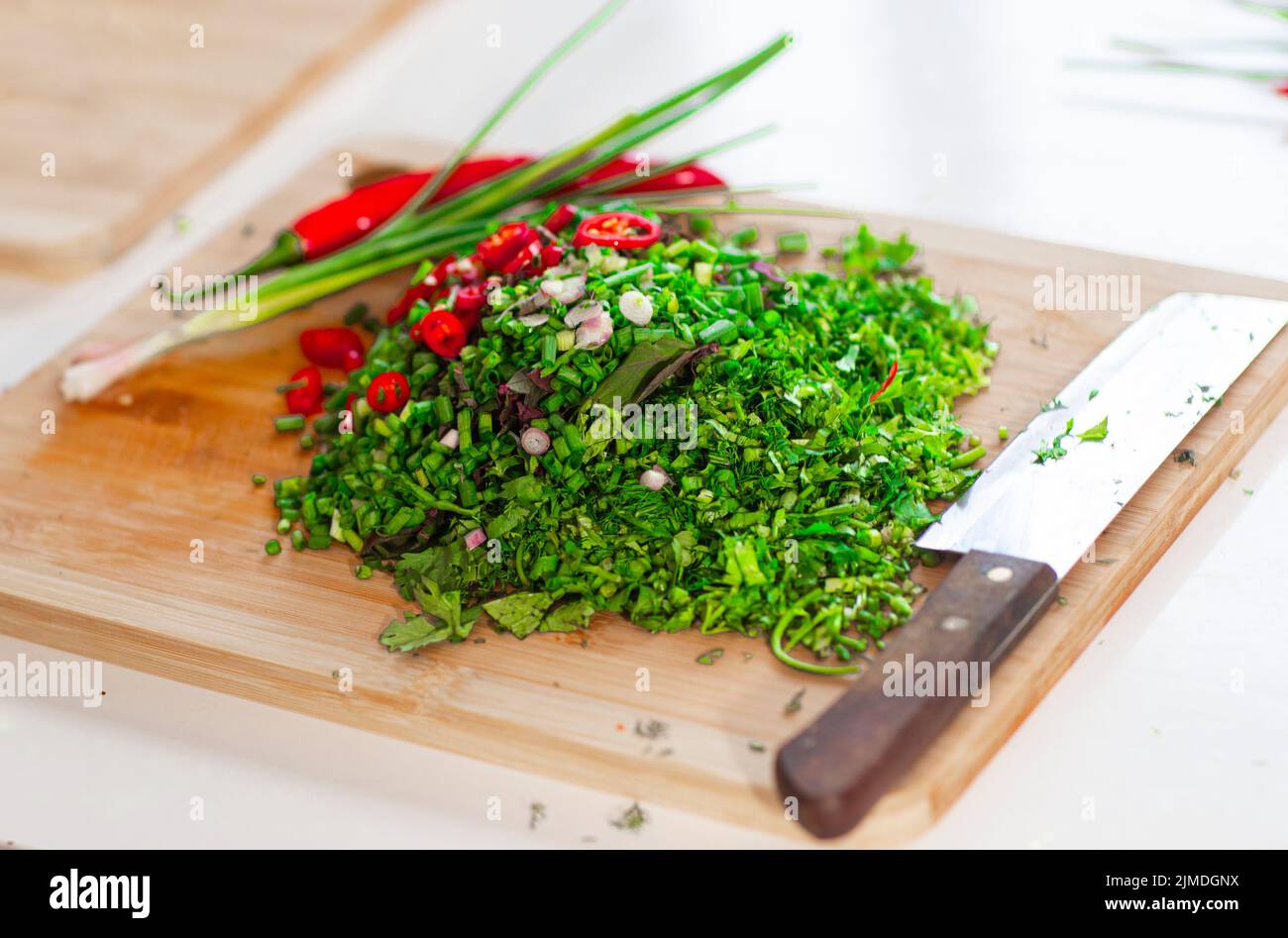 Knife and minced herbs. Green onion, chili pepper Stock Photo - Alamy