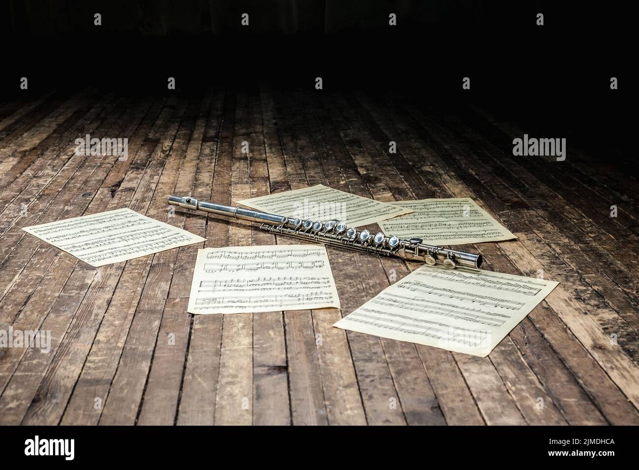 Flute lies on a wooden stage among sheet music with notes Stock Photo ...