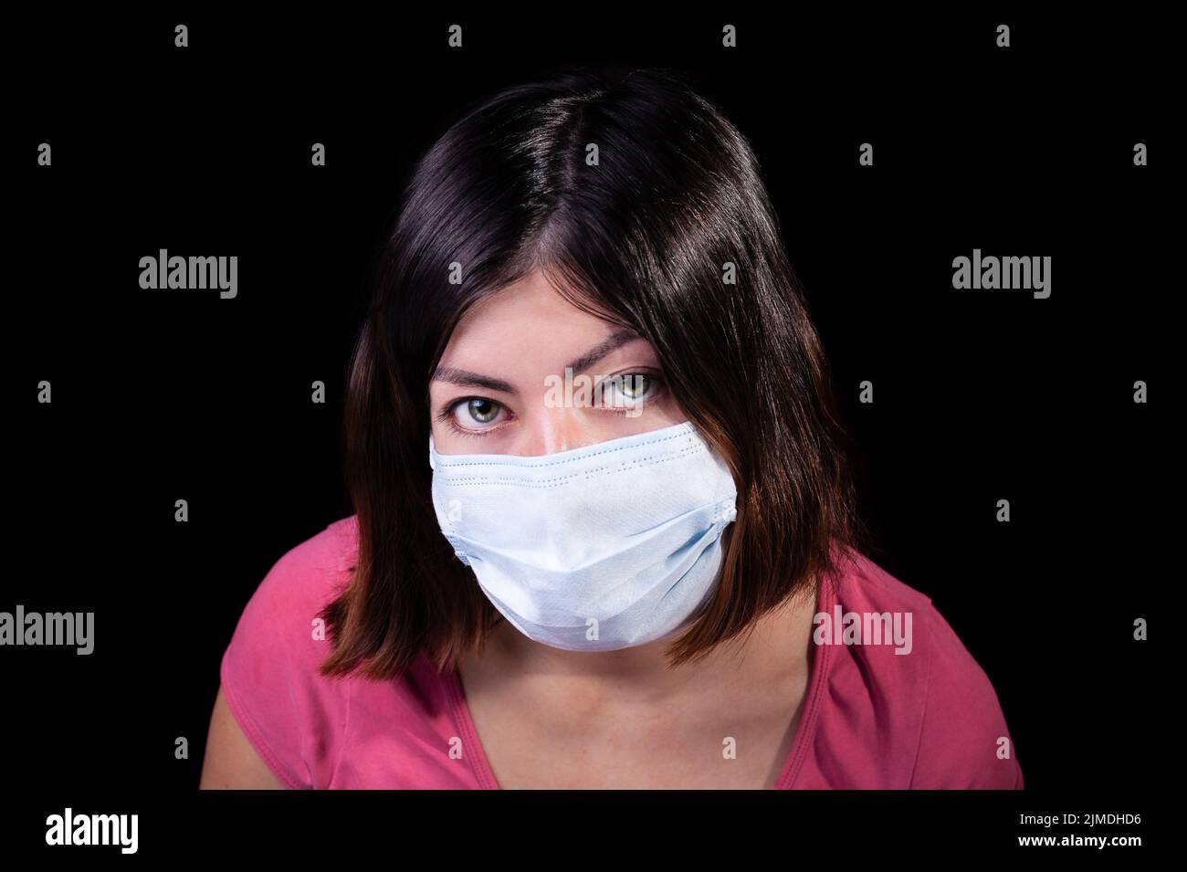Brunette young woman with green eyes with a white procedure face mask ...