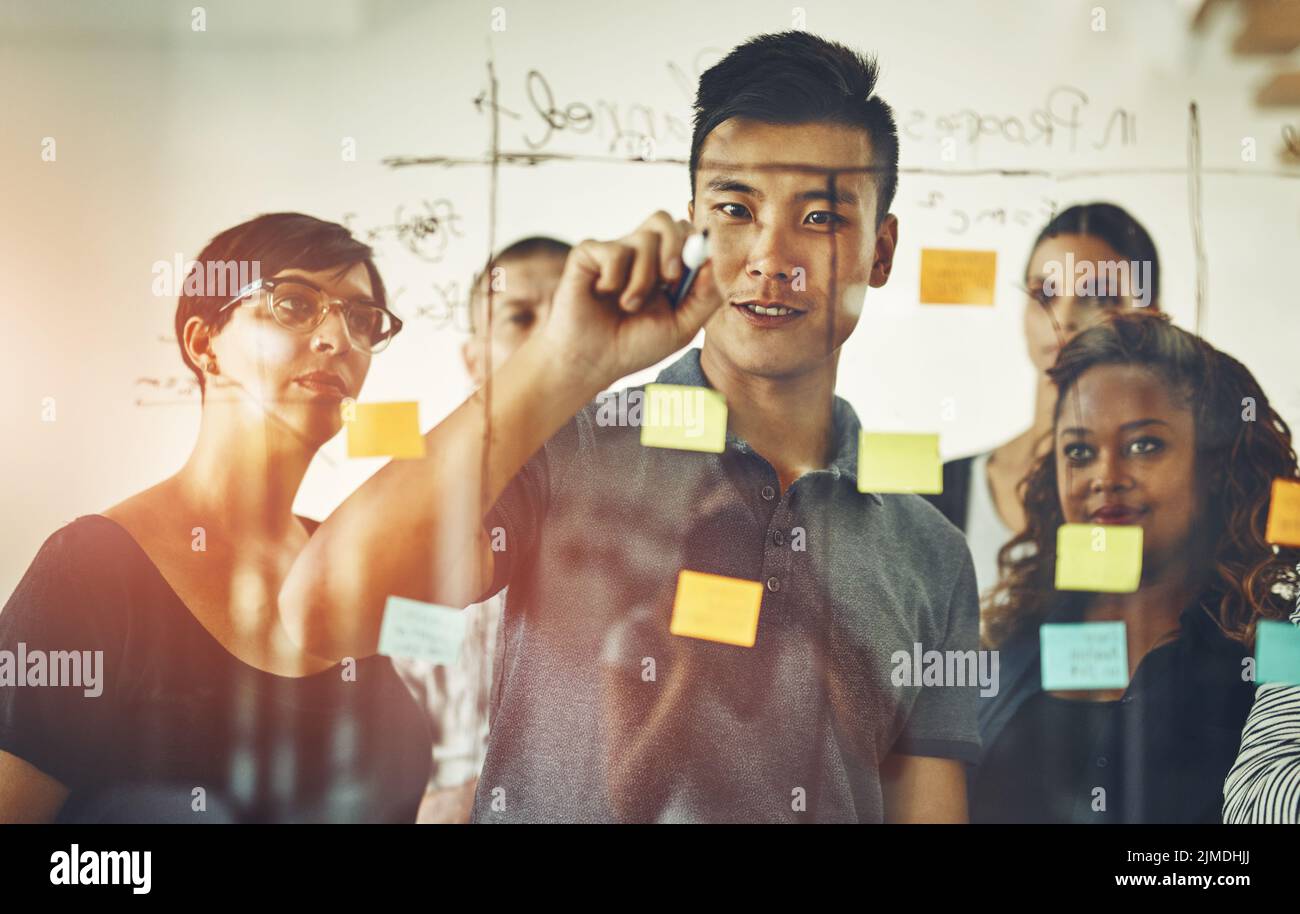 Team leader planning and writing on sticky notes while brainstorming ...