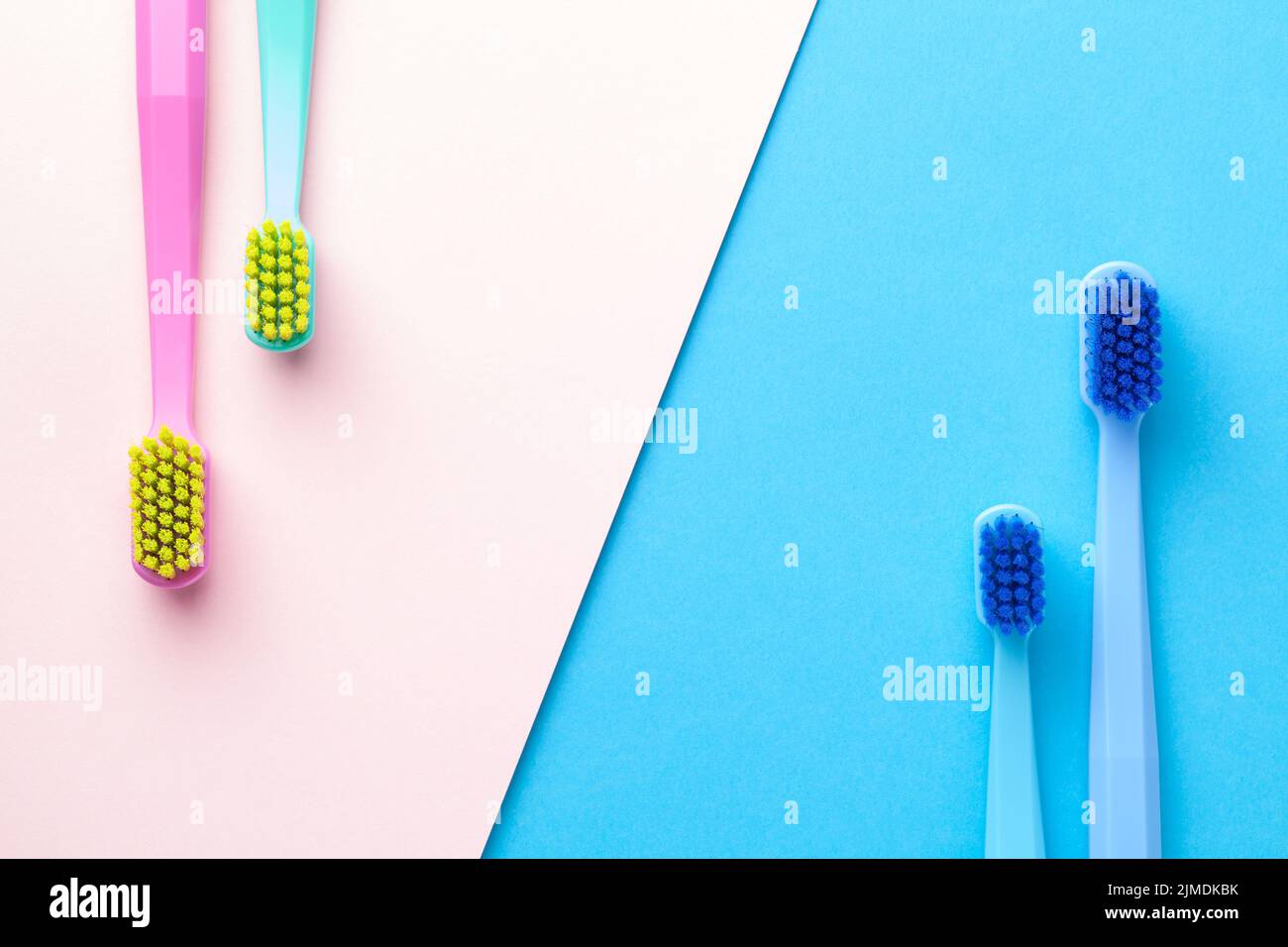 New Toothbrushes On Pink And Blue Paper Stock Photo - Alamy