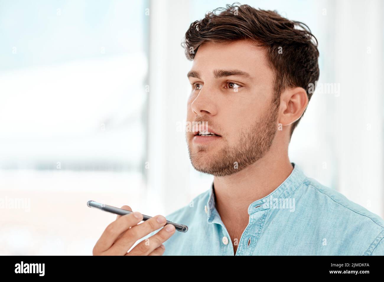 Sending a quick voice note. a handsome young businessman recording a ...