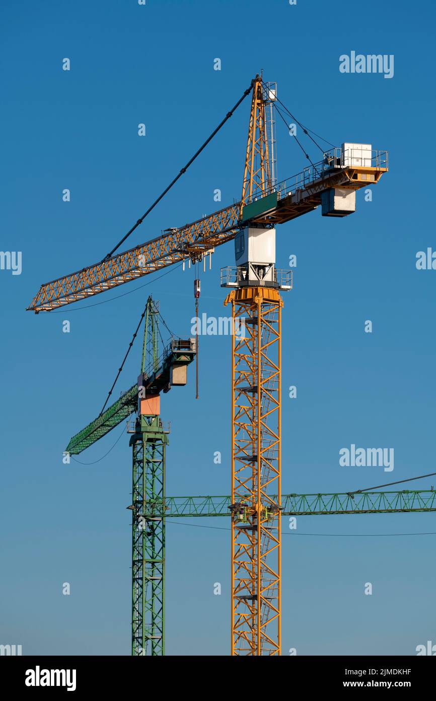 Three cranes in the evening light on a large construction site in the ...