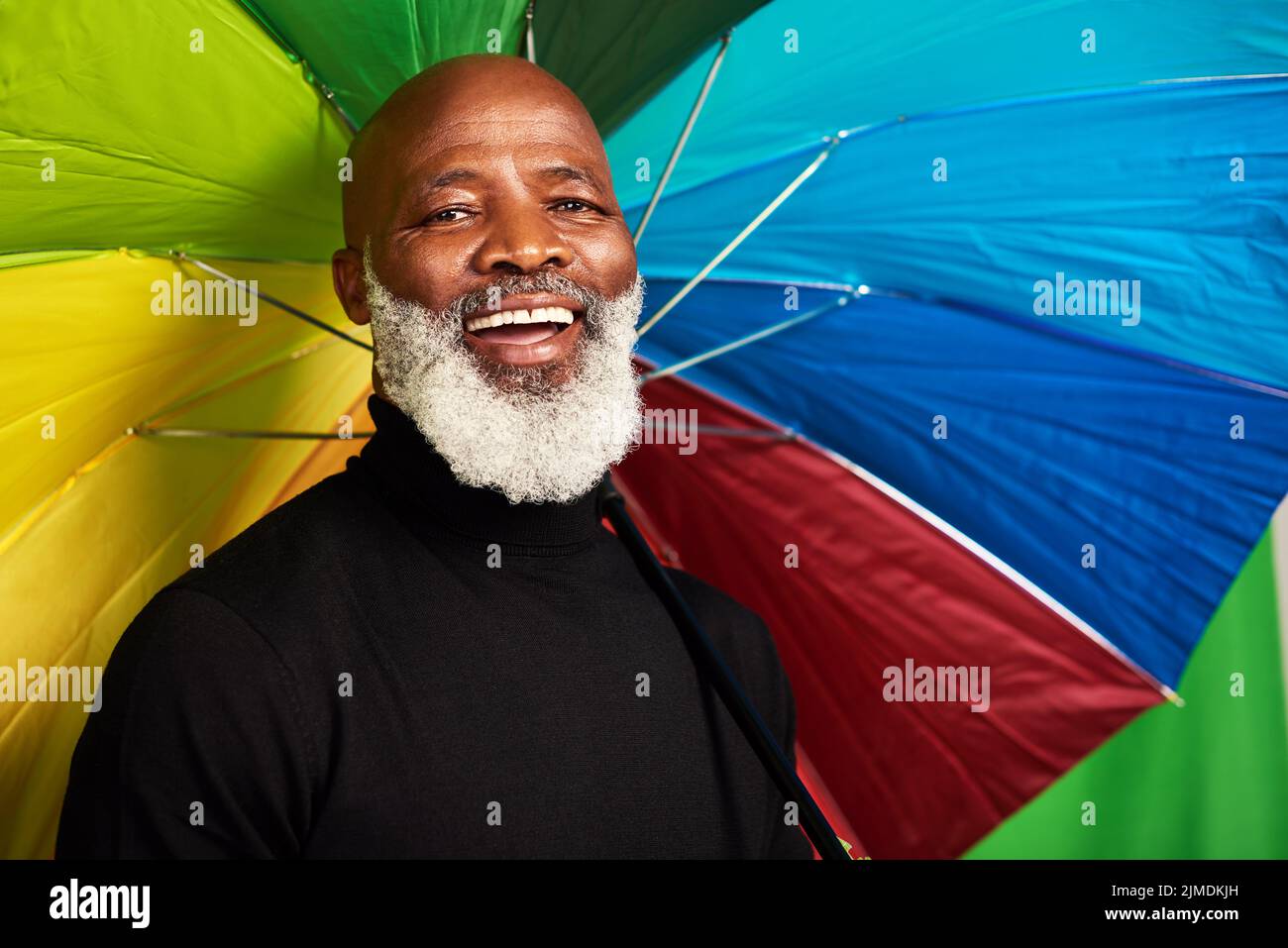 Keep yourself covered. a senior man posing with a colorful umbrella ...