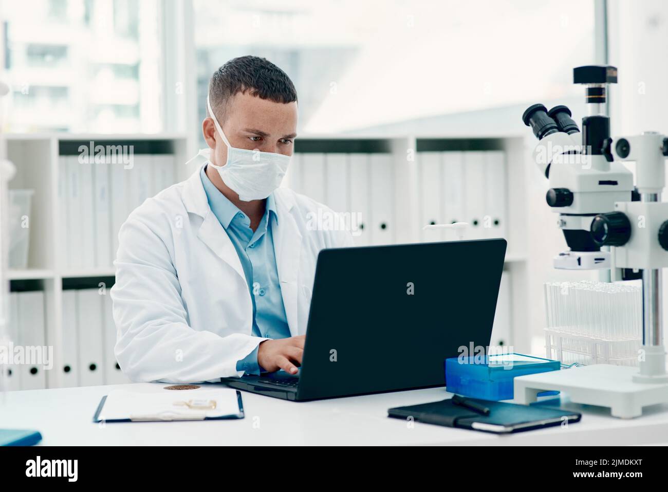 Time is ticking to find a cure. a young scientist using a laptop while ...