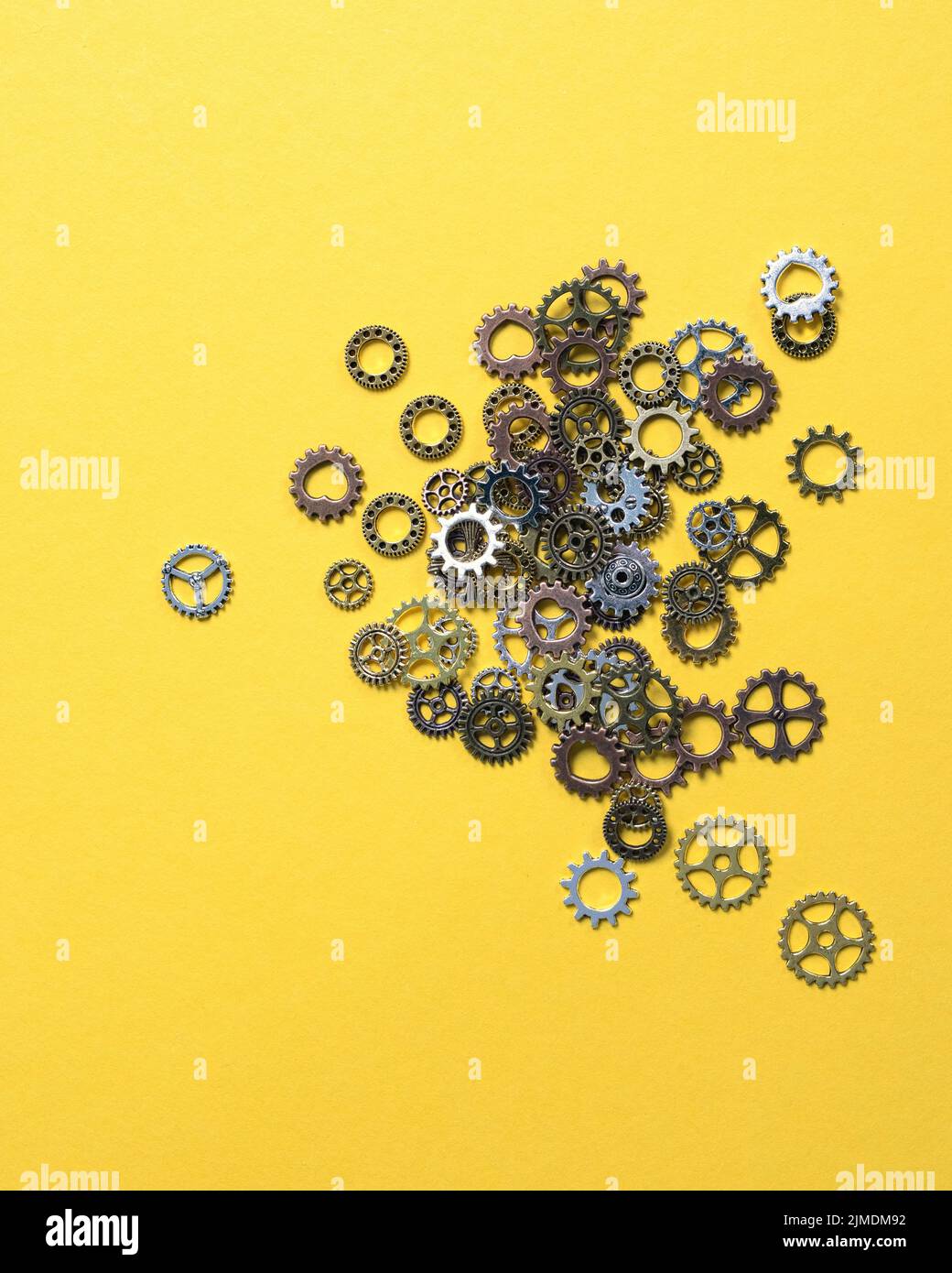 Brass cog wheels of different sizes lying on yellow background ...