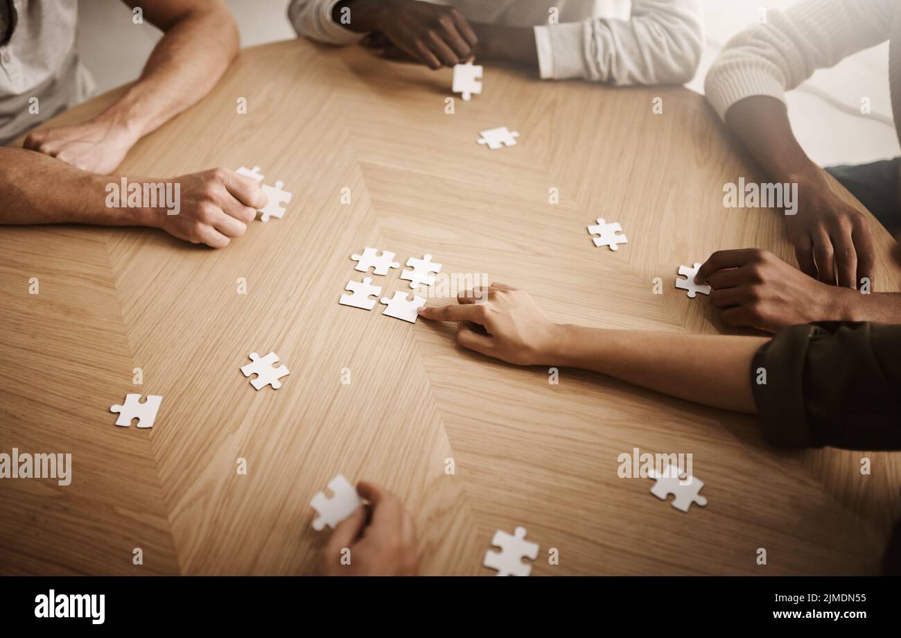 Friends hands solving a puzzle in a group collaboration together as a ...