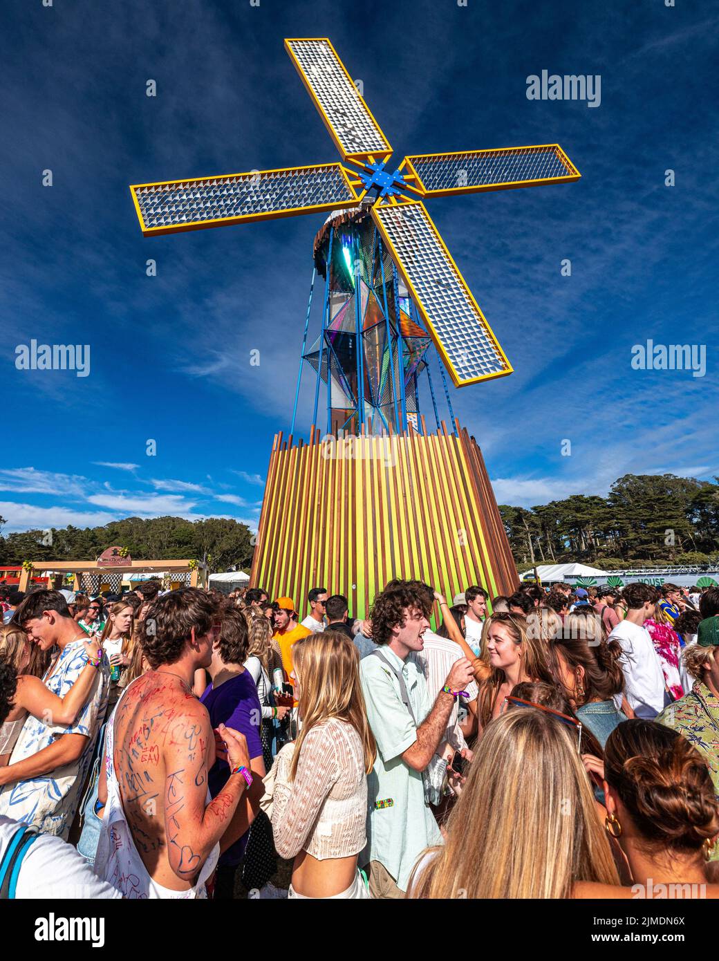 Crowd members walk past the windmill art installation during the ...