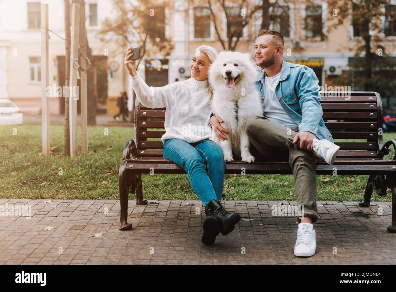 Spouses resting on bench with dog, making photo of themselves Stock ...