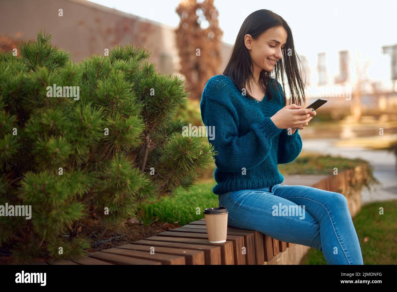 Charming female using mobile phone on a bench Stock Photo - Alamy