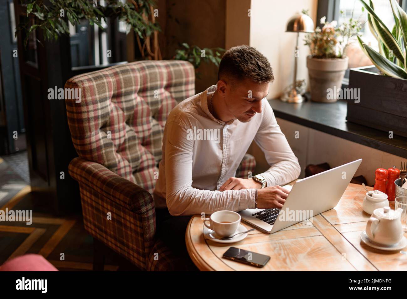 Happy guy typing on computer in coffee shop Stock Photo - Alamy