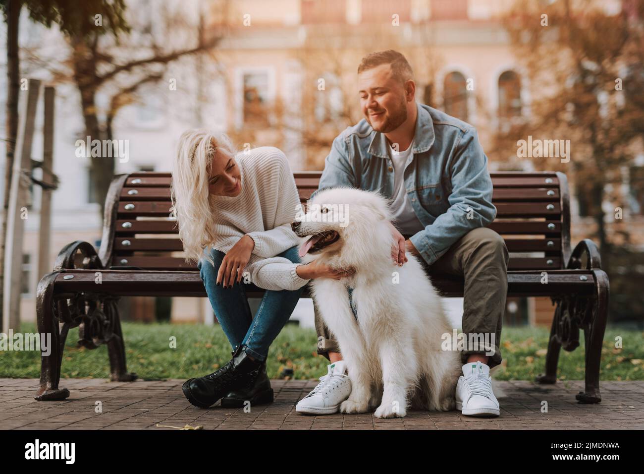 Happy couple having rest on bench, taking care of puppy Stock Photo - Alamy