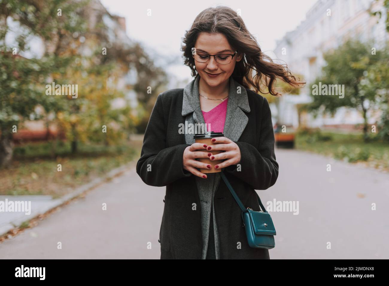 Lady enjoying hot coffee on windy day in the city Stock Photo - Alamy