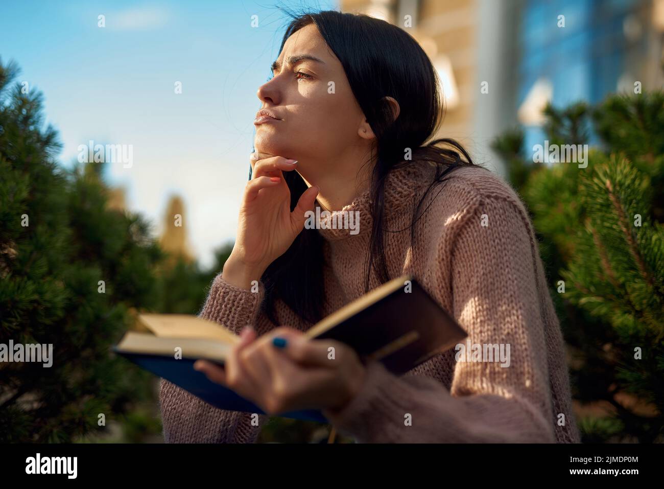 Serious woman thinking about something while reading outdoors Stock ...