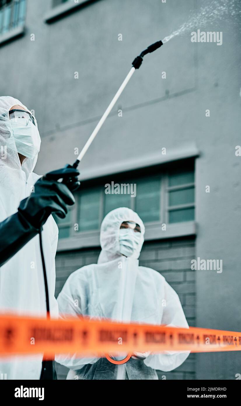 Healthcare workers wearing hazmat suits disinfecting a building during ...