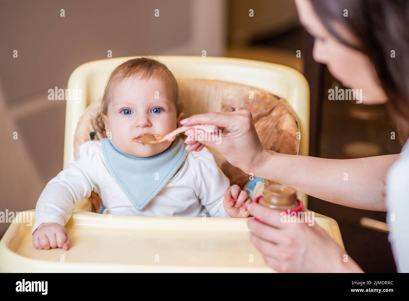 Mother feeds happy baby with fruit puree from a spoon. First food Stock Photo - Alamy