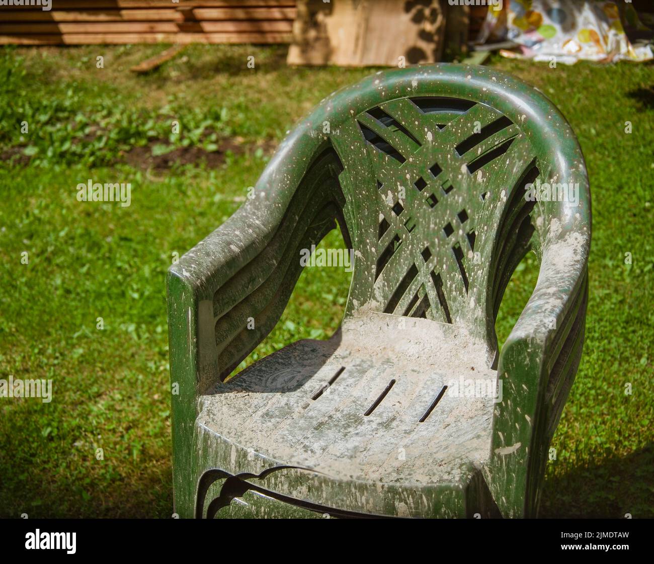 a stack of dirty plastic chairs, abandoned outside, sunny day shot ...