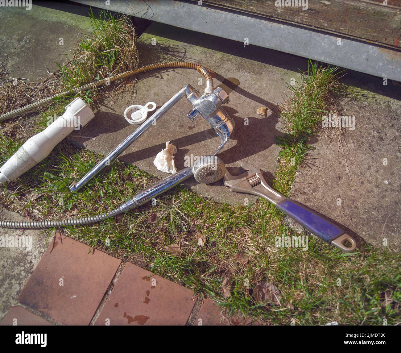 old bath hub and wrench abandoned on the ground in mess, outdoor sunny ...