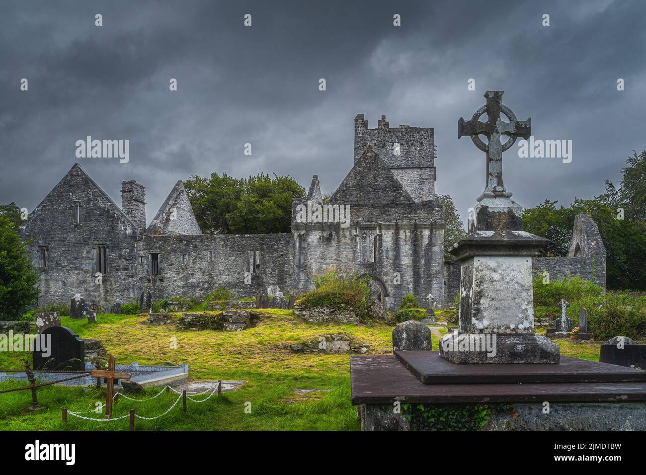 Ancient graveyard with Celtic cross tombstone and ruins of 15th century ...