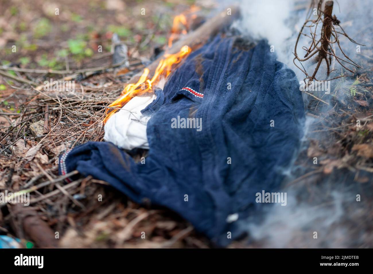 pile of old clothing burning in a campfire, outdoor shot, shallow DOF ...