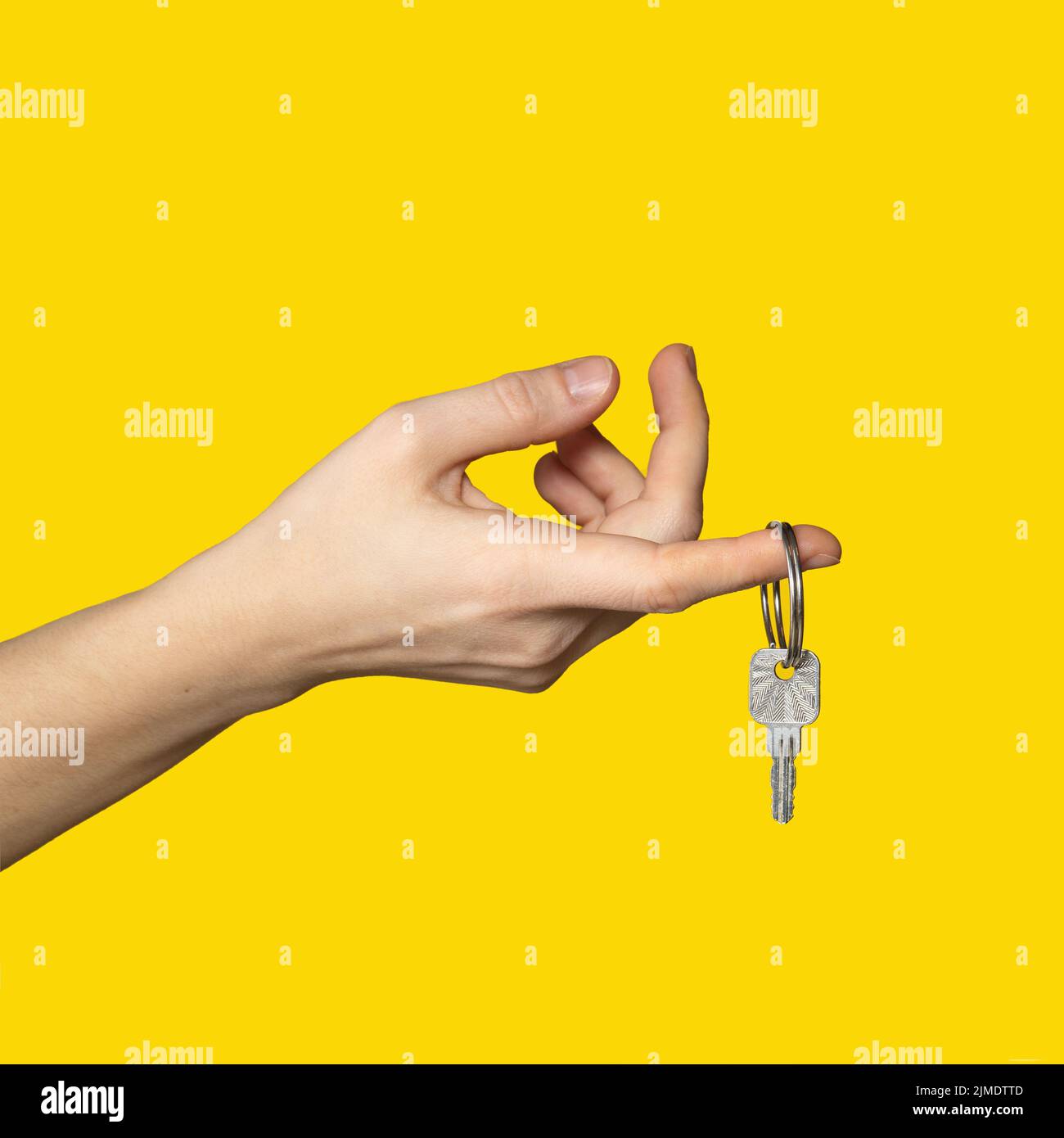 On finger of woman hand hangs key on bright yellow background Stock ...