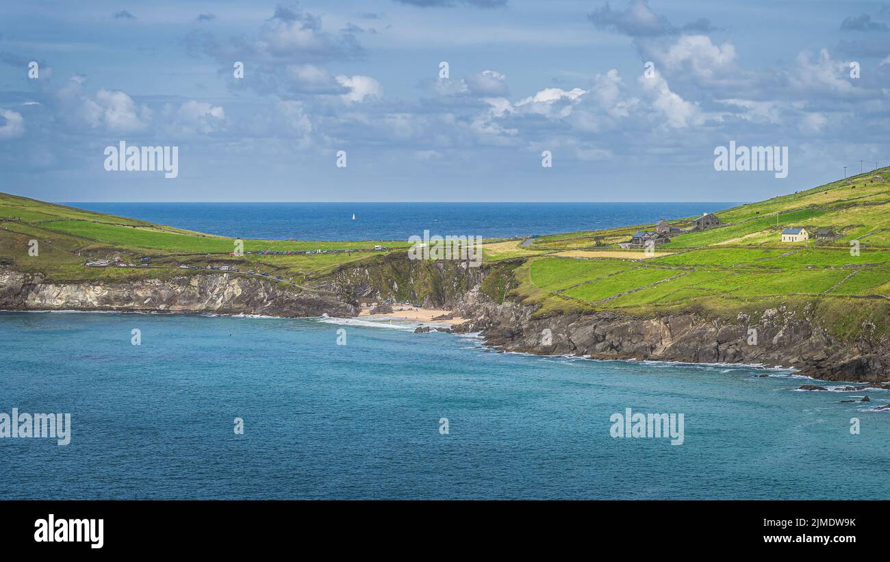 Tourist relaxing on small hidden Coumeenoole Beach between cliffs in ...