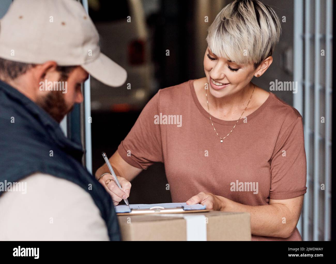 Your delivery will always arrive on time. a young woman signing for a ...