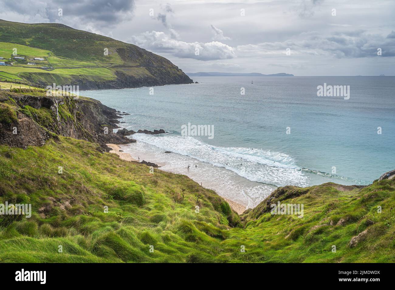 People swimming in turquoise coloured sea between cliffs in Dingle ...