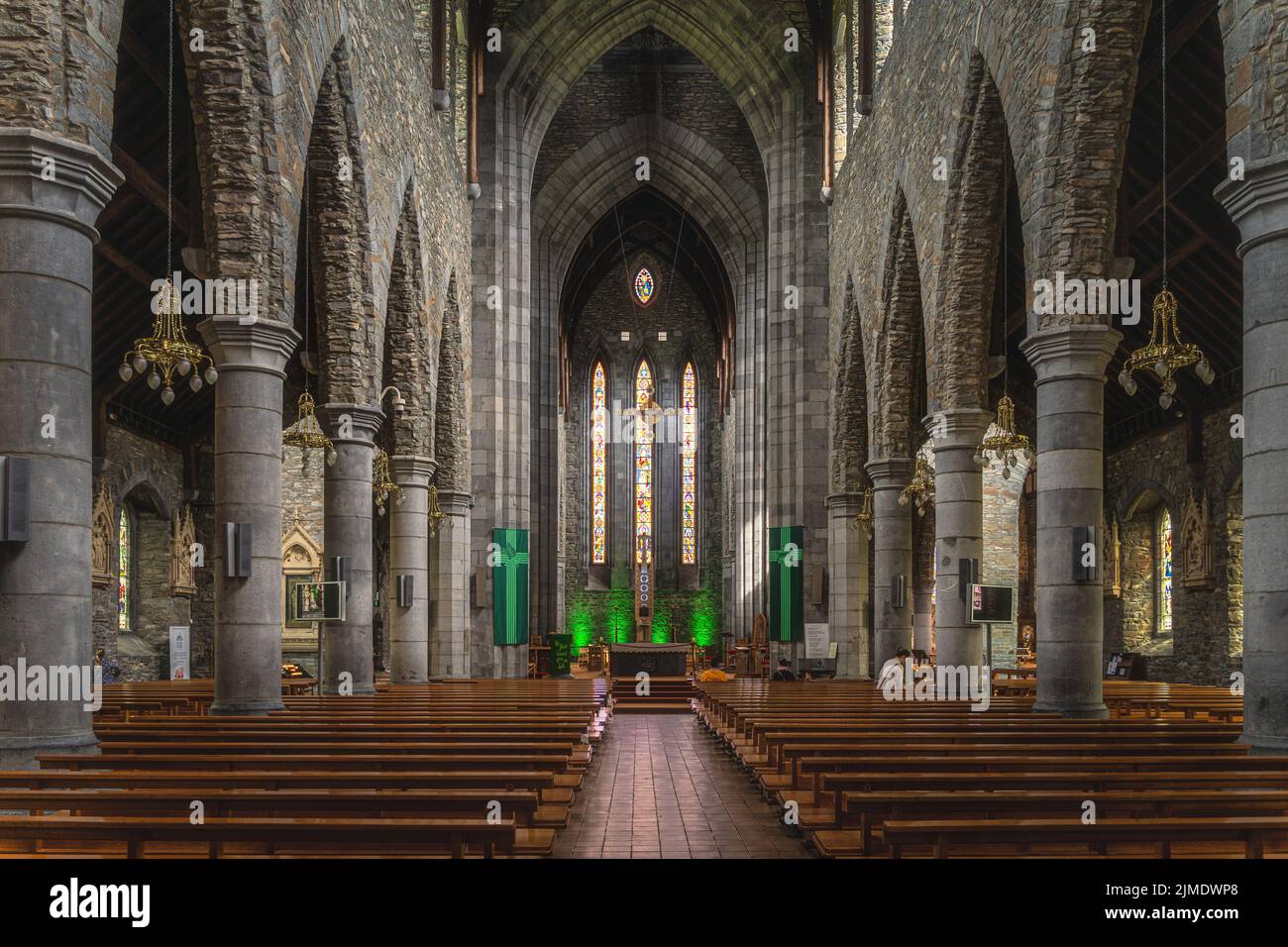 Rows of benches, tall columns, stained glass and main altar in St ...
