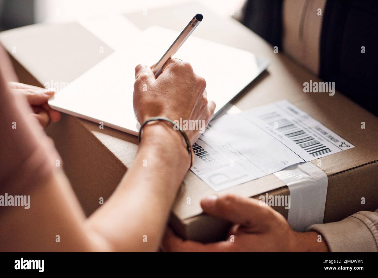 Signing to confirm proof of delivery. Closeup shot of an unrecognisable ...
