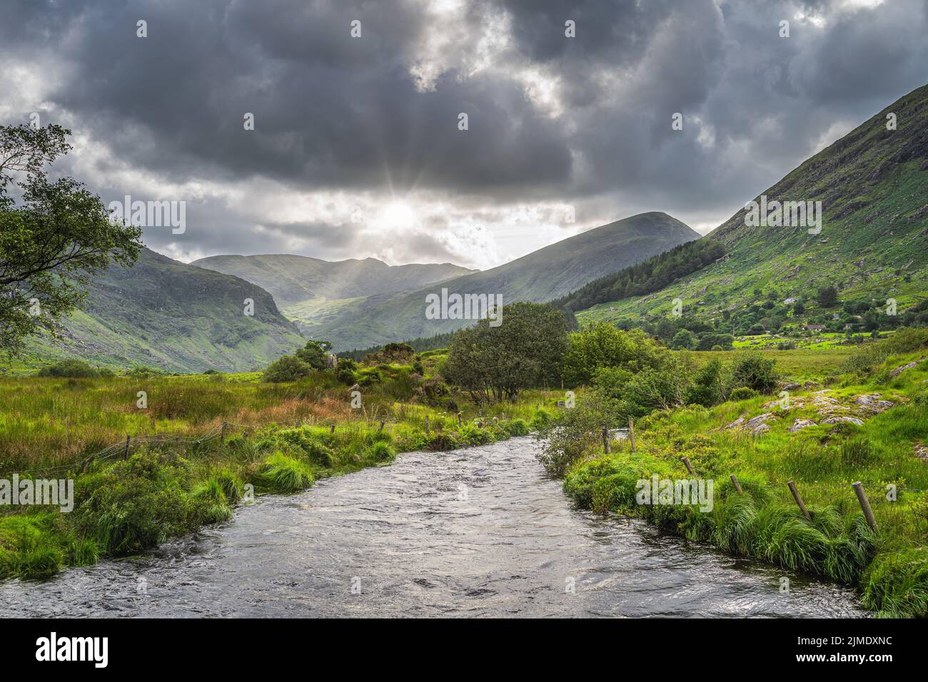 River running trough beautiful Black Valley with dramatic sky and sun ...