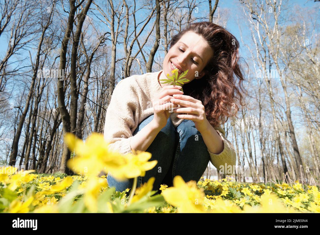 Woman enjoying smell of spring flowers. Smiling woman among spring ...