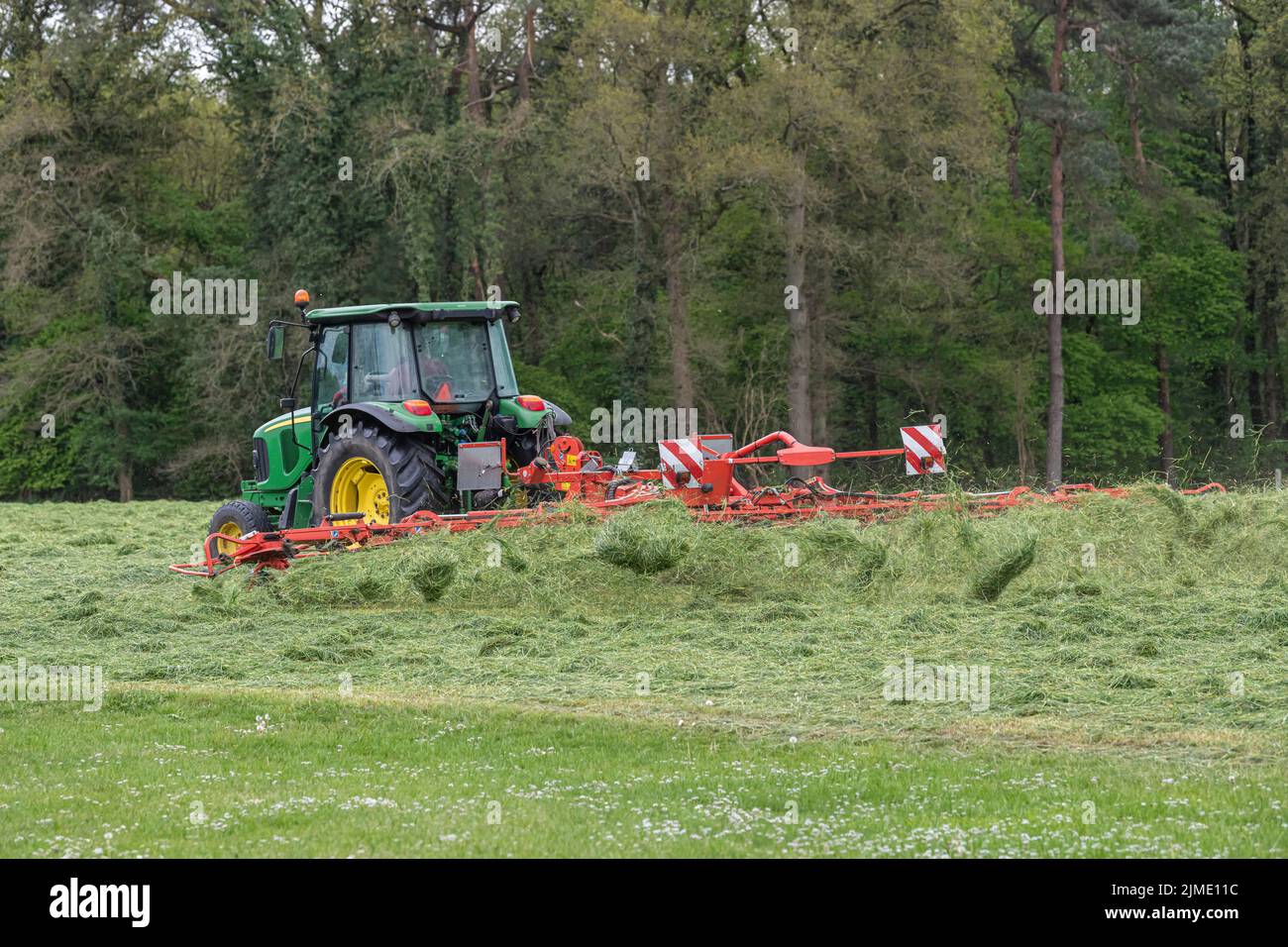 Shaking of freshly cut grass with tractor and tedder Stock Photo - Alamy