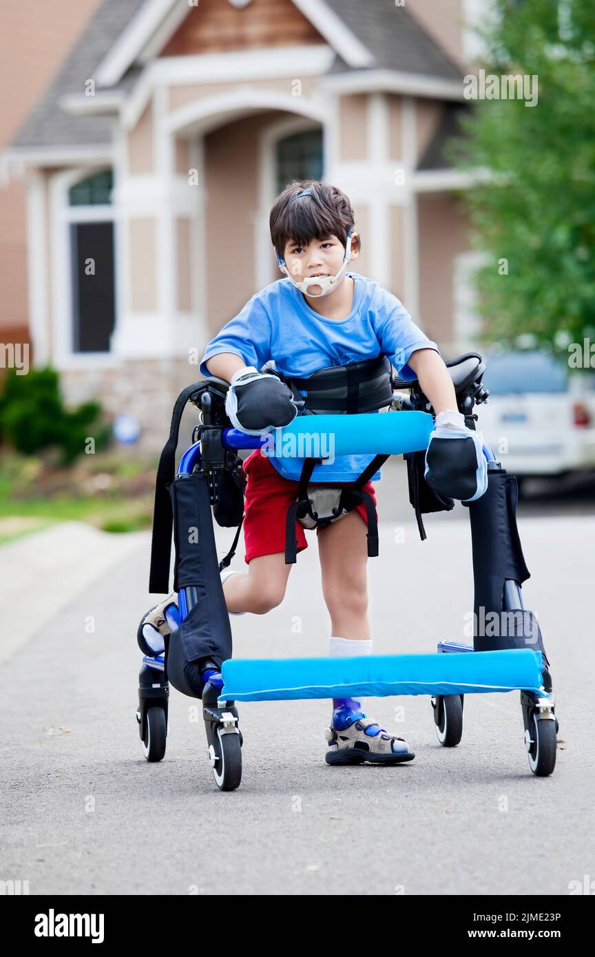 Six year old disabled boy walking in walker down the street Stock Photo ...