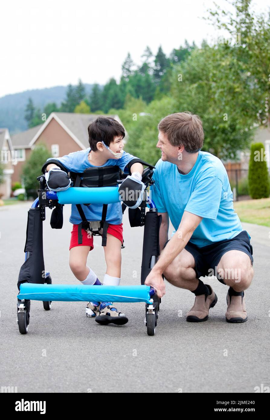 Father kneeling next to disabled son standing in walker Stock Photo - Alamy