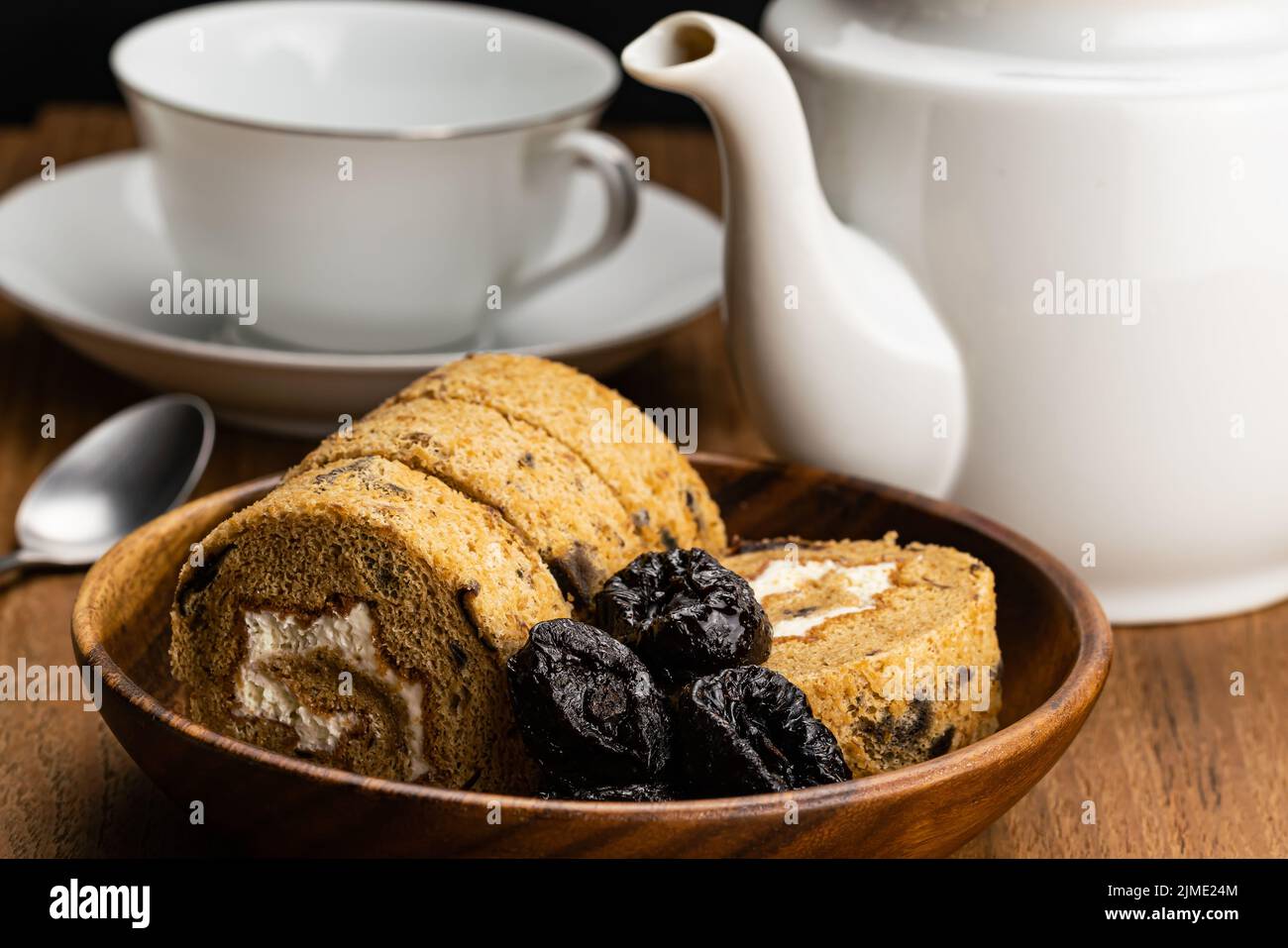 Side view of homemade prune sponge cake roll and dried pitted prune ...