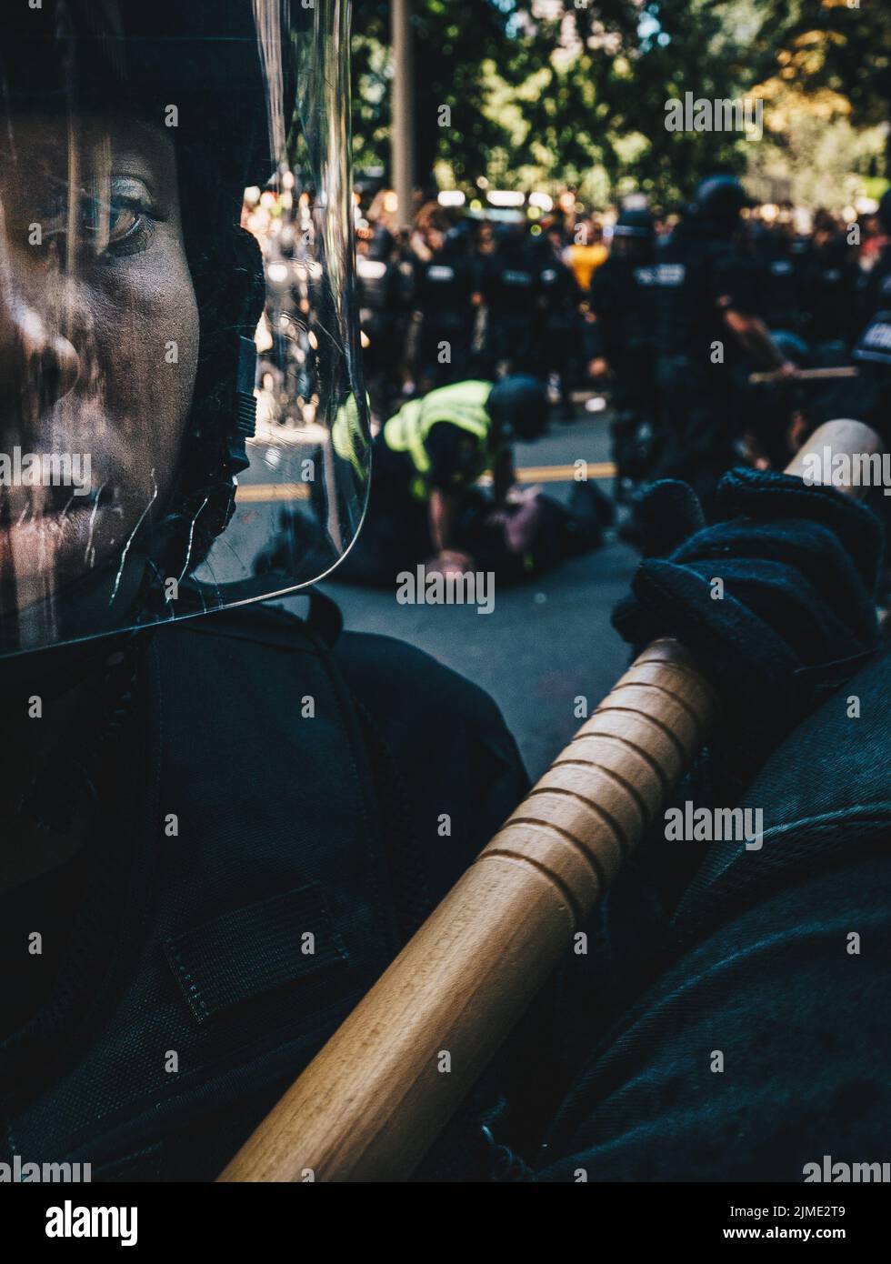 The vertical view of a police officer with a stick another protestor ...