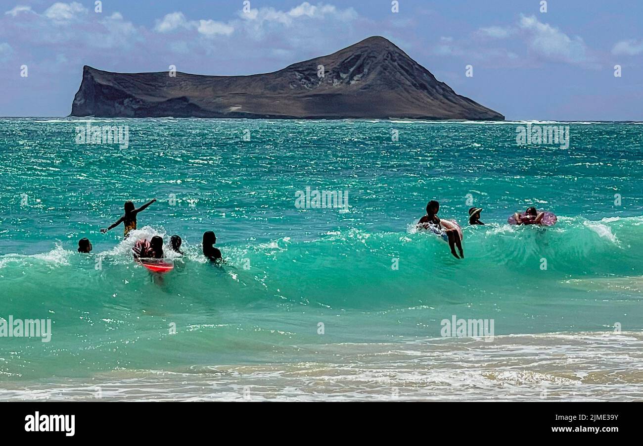 Young people playing in shallow surf on Oahu beach Stock Photo - Alamy