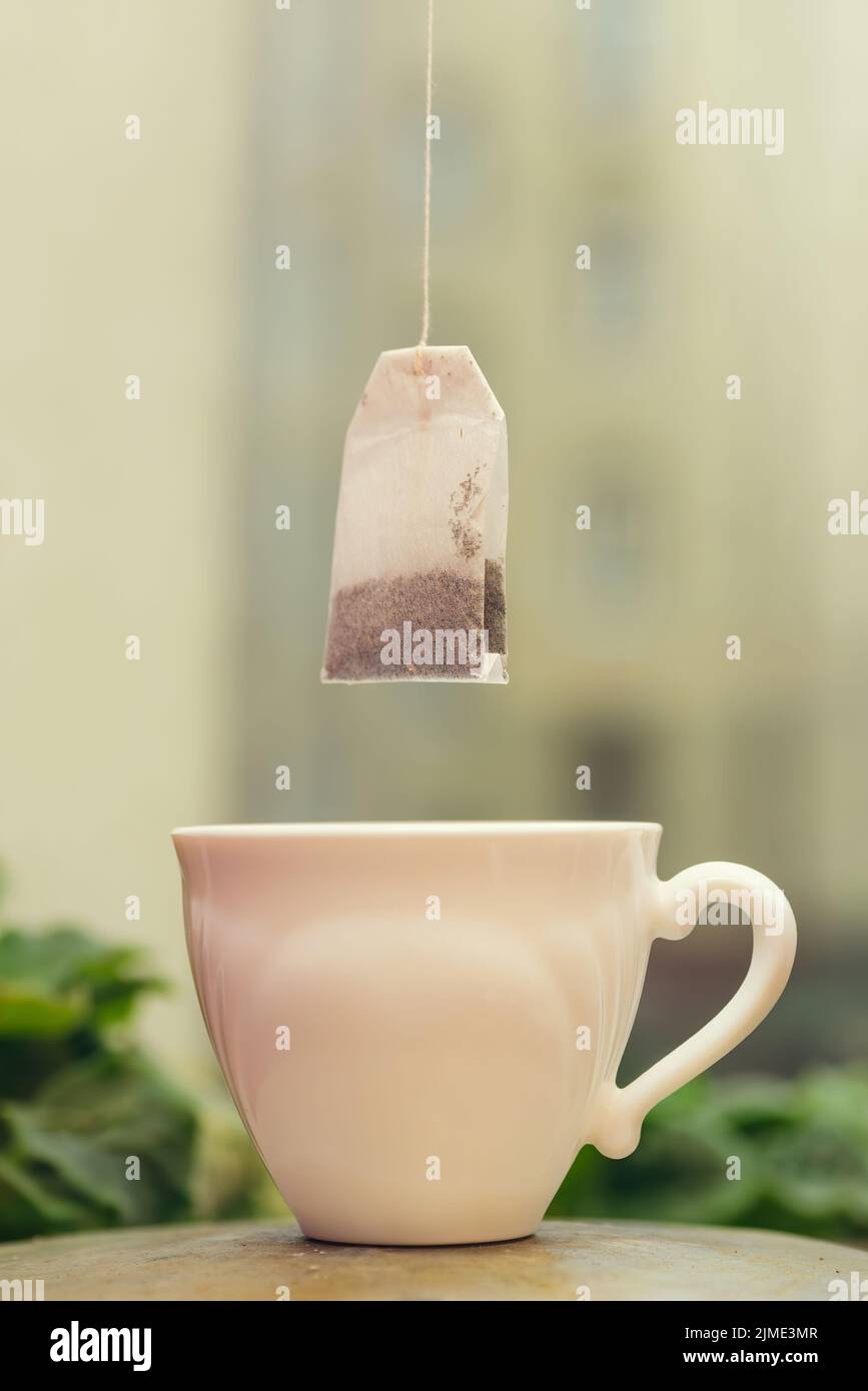 Dry new disposable tea bag hanging over a white mug Stock Photo - Alamy