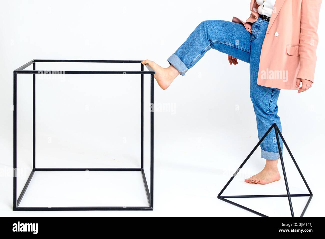 A young woman stands barefoot with her leg over the skeleton of a cube ...