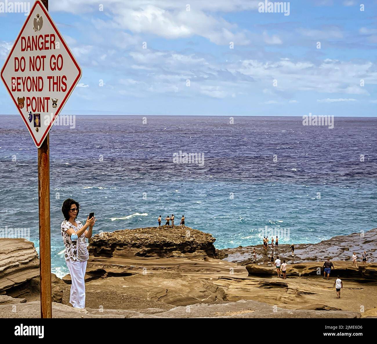 Honolulu, Hawaii - Nov 6, 2021-People stand on beach rocks beyond the ...