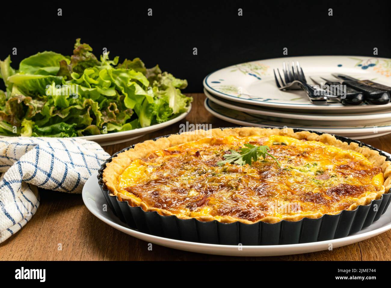 Side view of homemade bacon spinach quiche in black metal oven pie ...