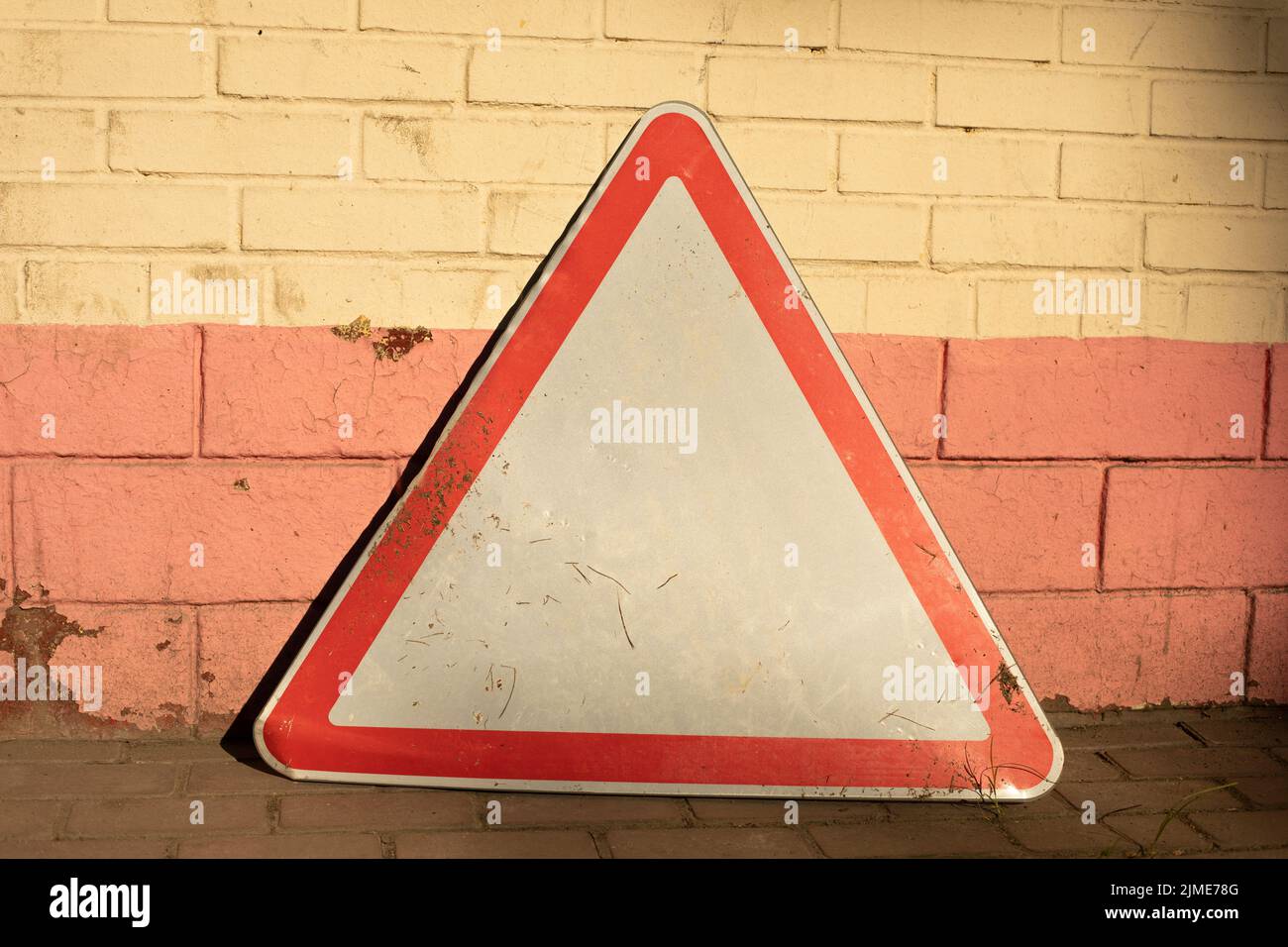The road sign stands against the wall. The triangle symbolizes traffic ...
