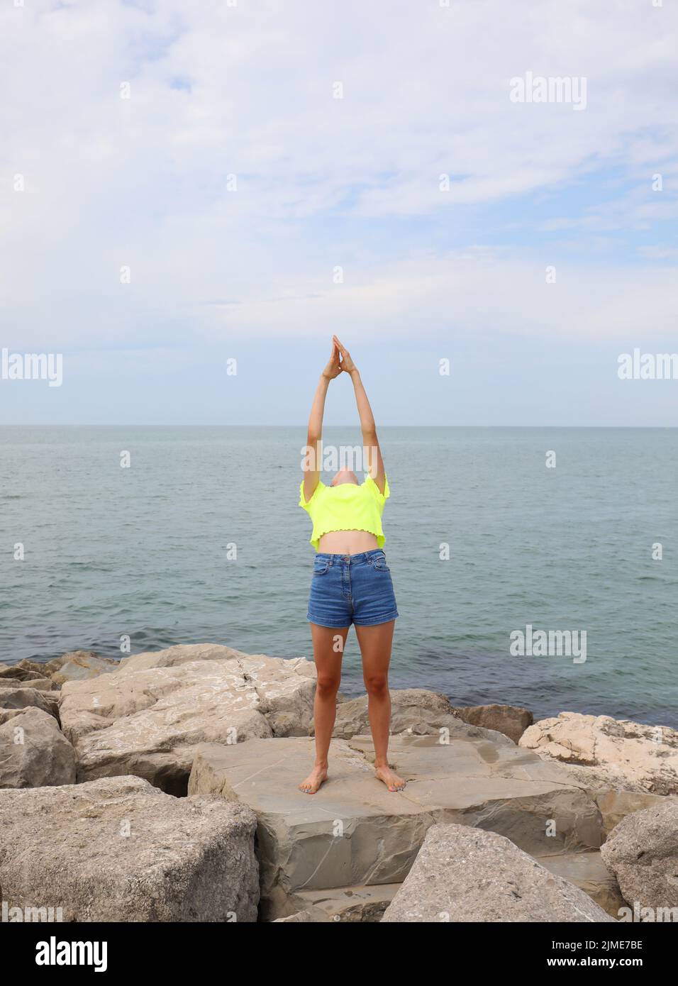 girl in a yellow shirt giving a gymnastic exercise on the rocks arching ...