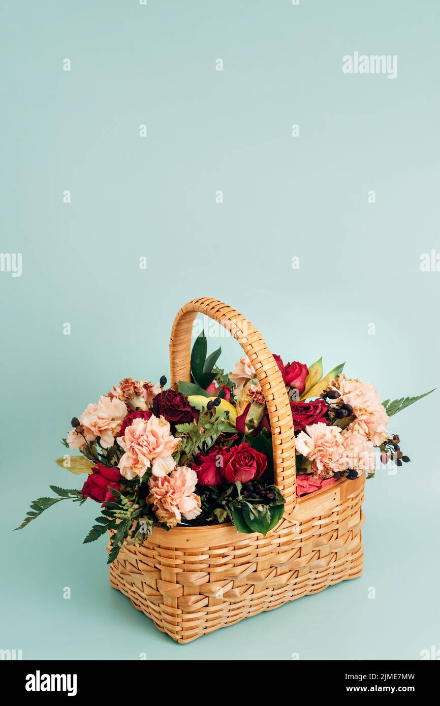 A widling bouquet of summer flowers in a wicker basket stands on a ...