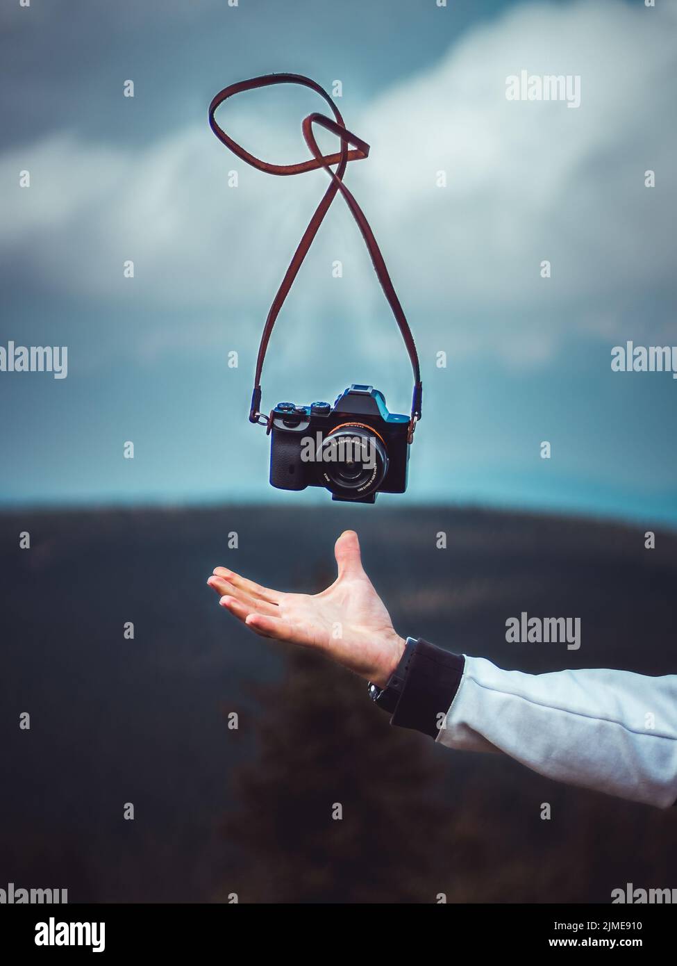 A mirrorless camera thrown into the air flying above human open palm ...