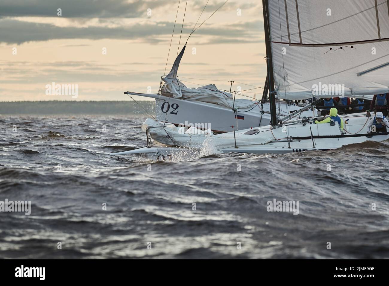 Competition of two sailboats on the horizon in sea at sunset, the amazing storm sky of different ...