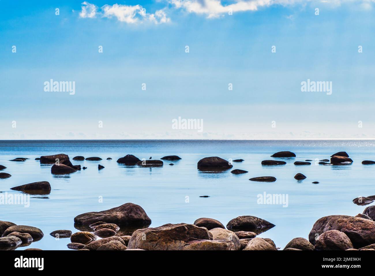 Stone Boulders in the Calm Waves of the Azure Ocean Against a Blue Sky ...